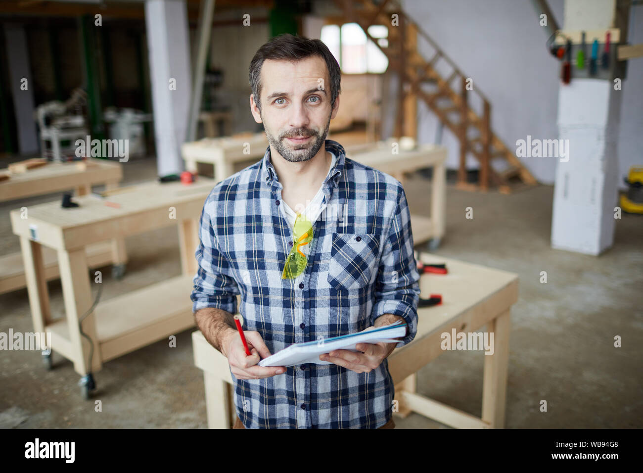 Waist up portrait of mature carpenter looking at camera while standing ...
