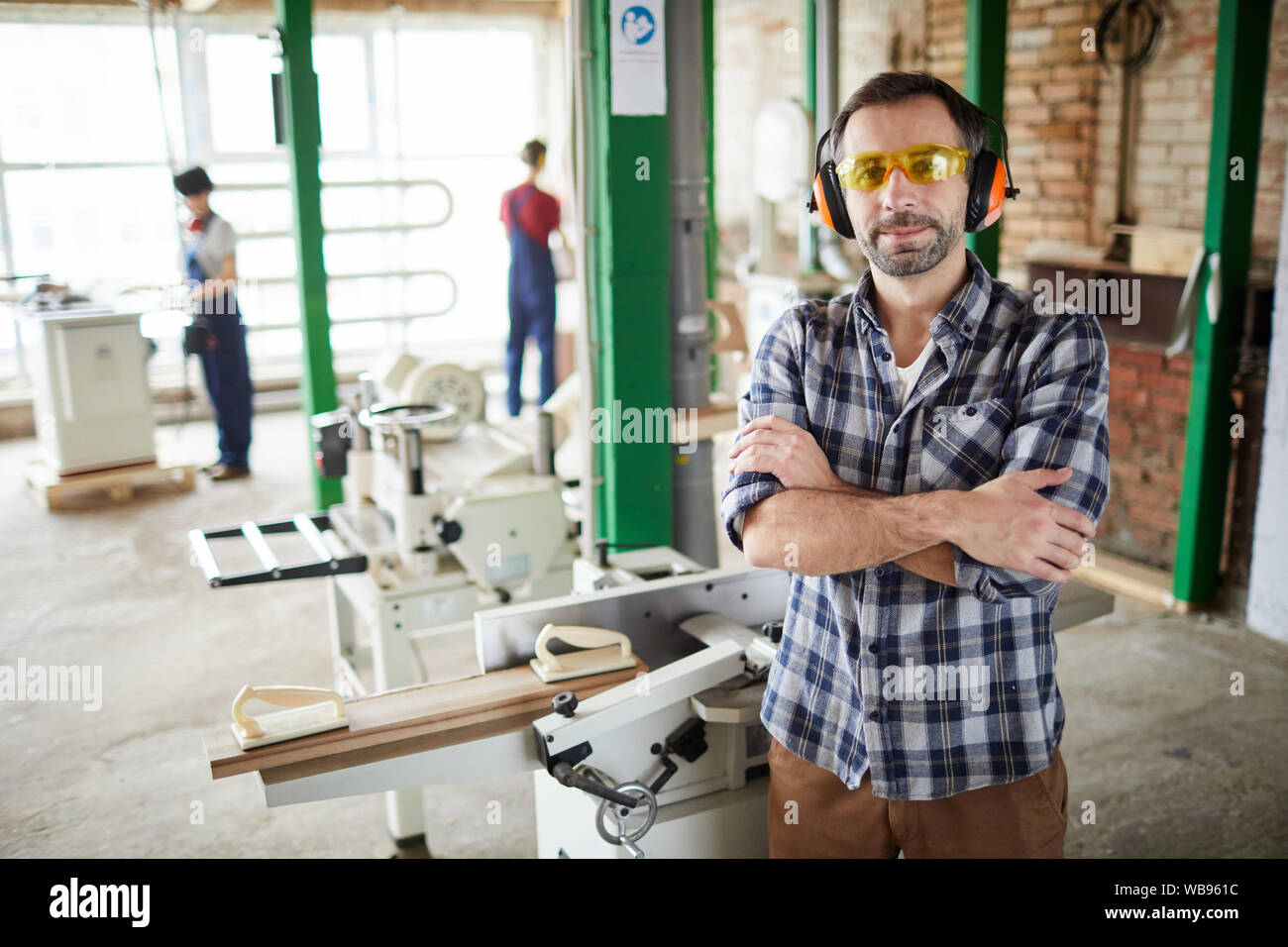 Waist up portrait of confident mature carpenter standing with arms ...