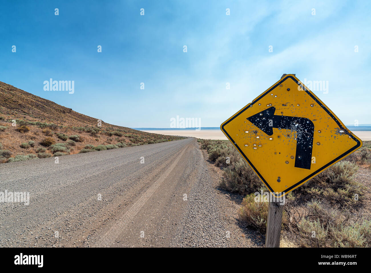 Shot up sign showing a curve to the left in the Alvord Desert in Harney ...