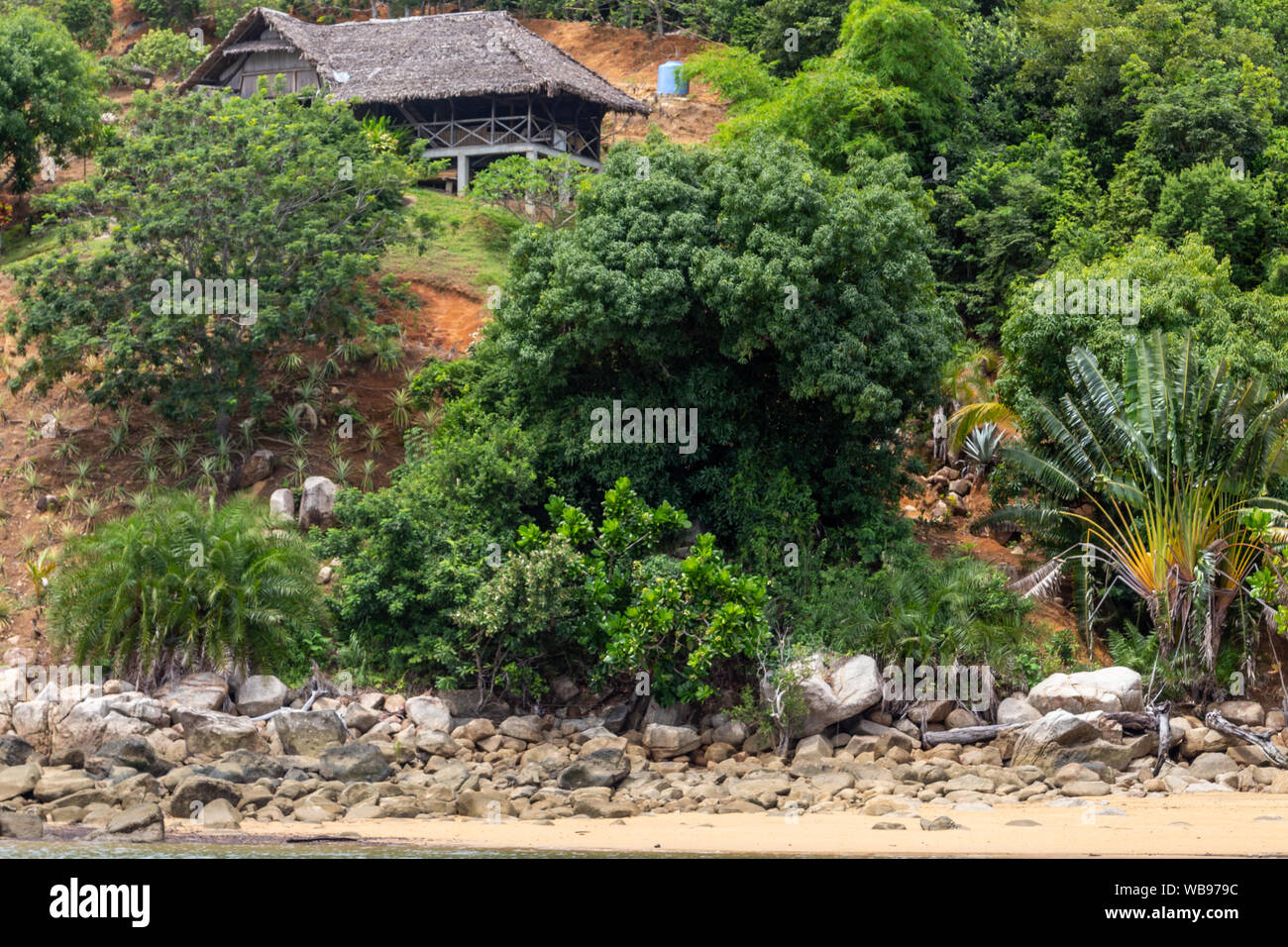 Beach with palm trees and wooden cottage, green mountains at Lokobe ...