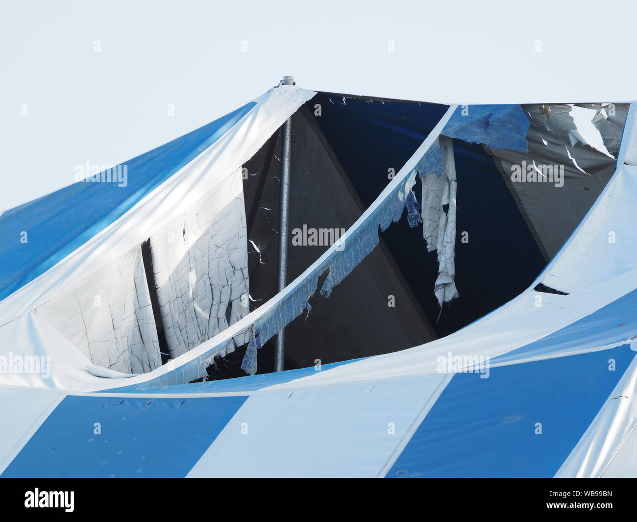 Ragged tent. Big hole. Striped blue-white fabric Stock Photo - Alamy