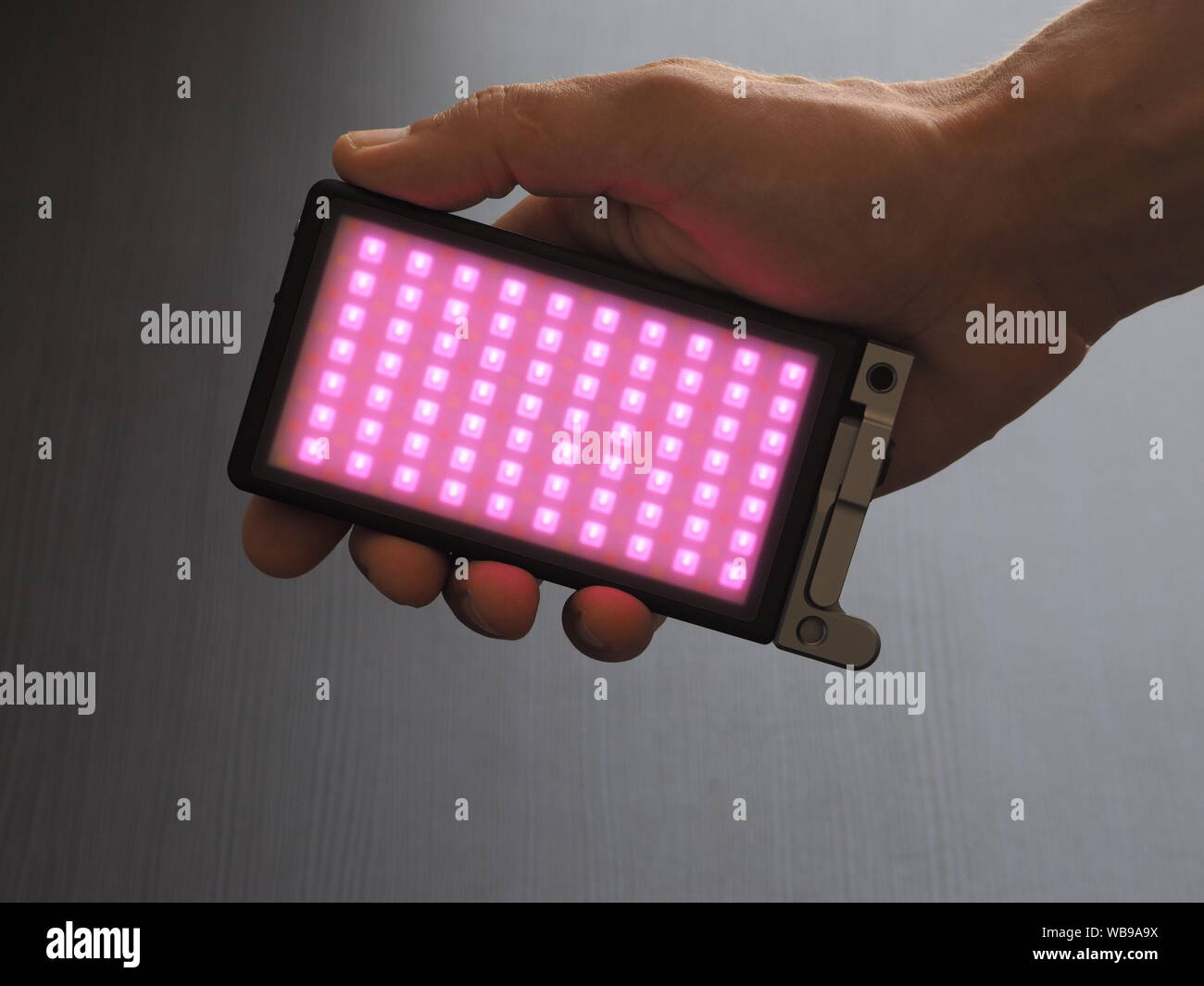 Portable RGB light on a man hand, dark background. Pink light Stock ...