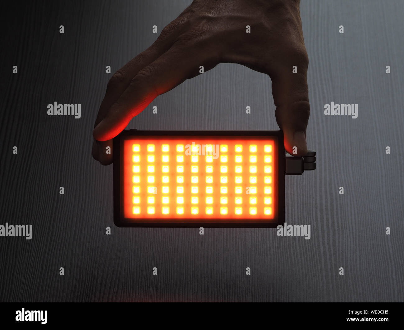 RGB light on a man hand, dark background. Orange light Stock Photo - Alamy