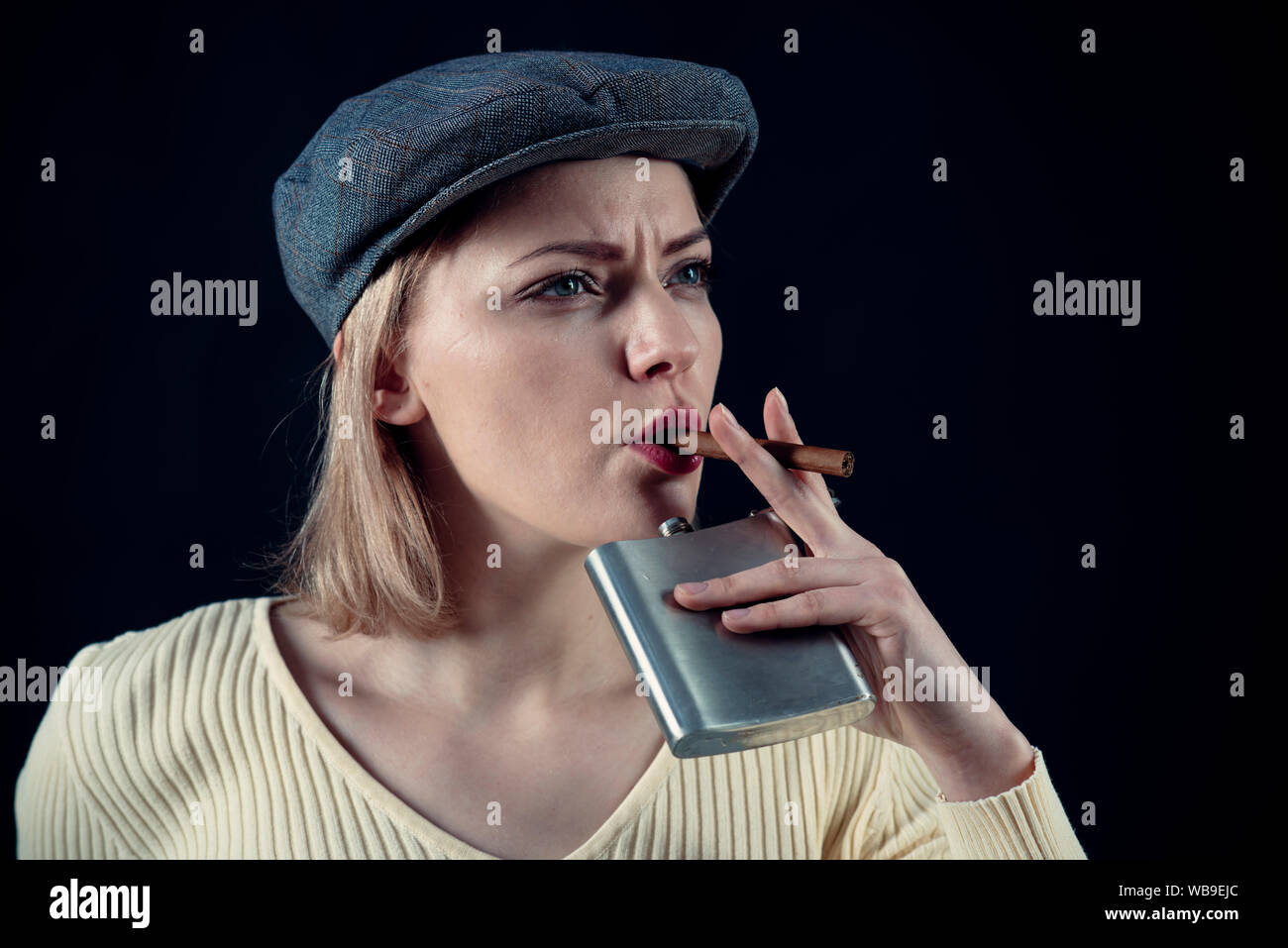 Girl thinking about investigation, holds flask and smoking cigar, copy ...