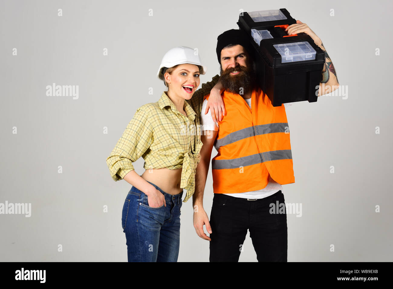 Repairman with girlfriend, copy space. Smiling woman in helmet excited ...
