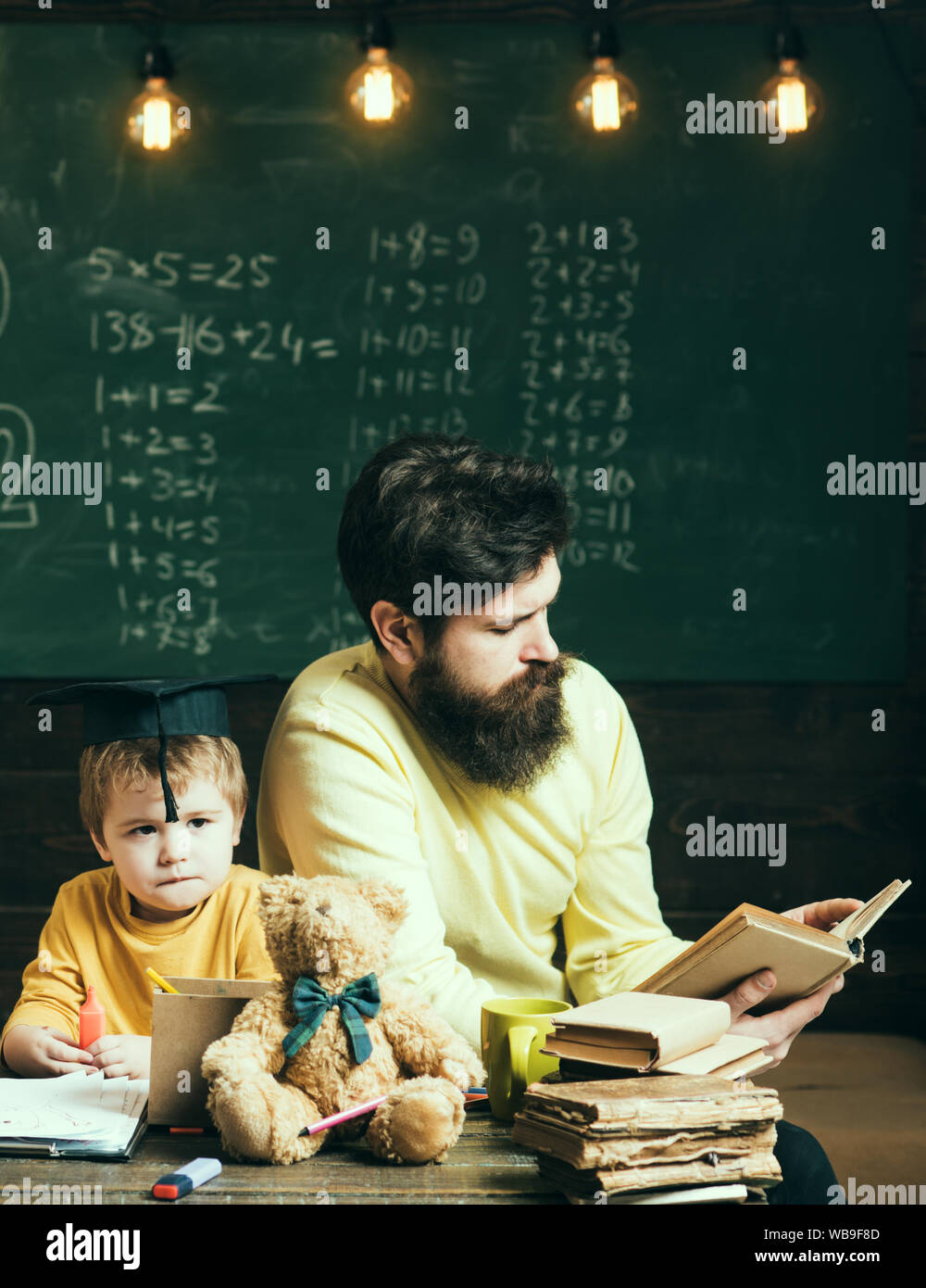 Wunderkind and genius concept. Father, teacher reading book, teaching ...