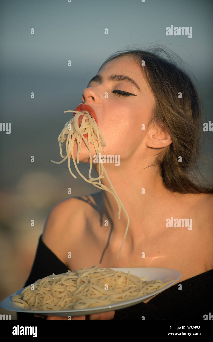 Hunger, appetite, recipe. Chef woman with red lips eat pasta. Woman ...