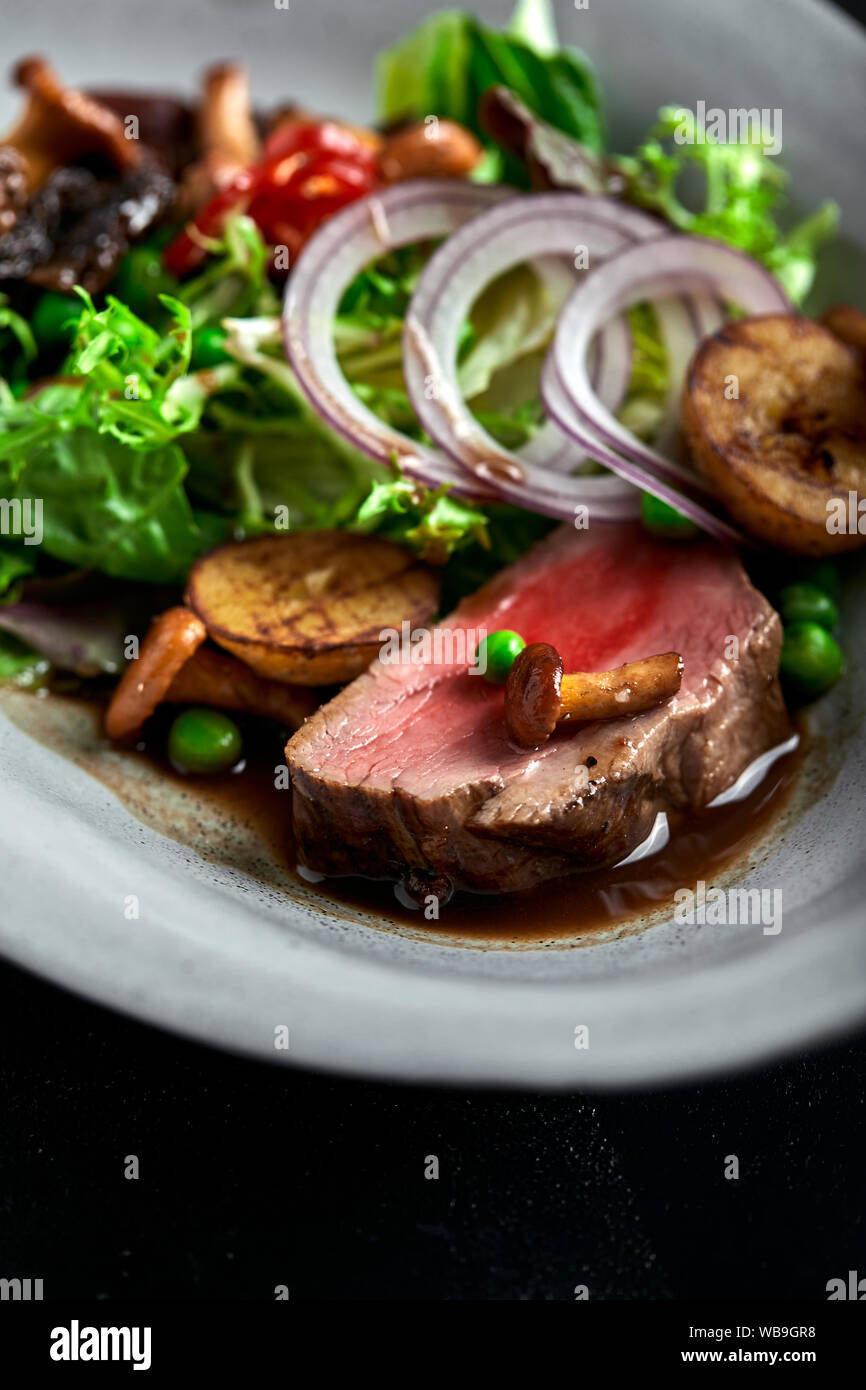 beef tagliata with vegetables. Close-up, low key, gray background Stock ...