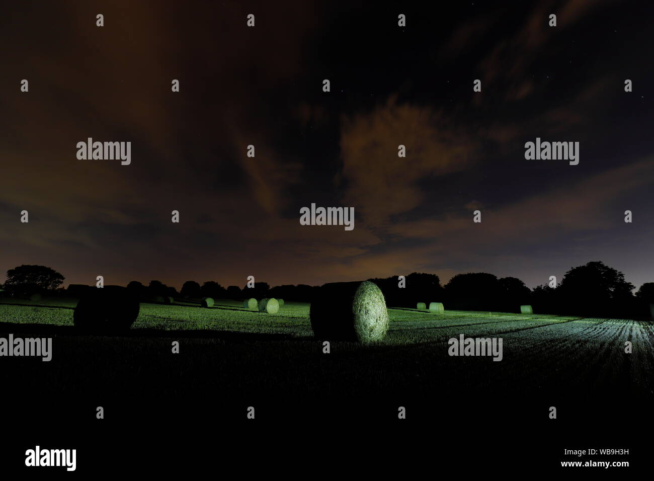 Hay bales lit up at night by torchlight Stock Photo - Alamy