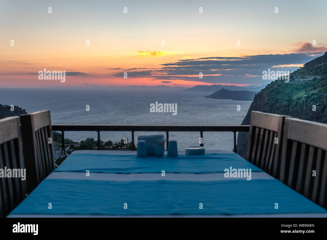 Sunset in the distance over the ocean with mountains and dinner tables ...