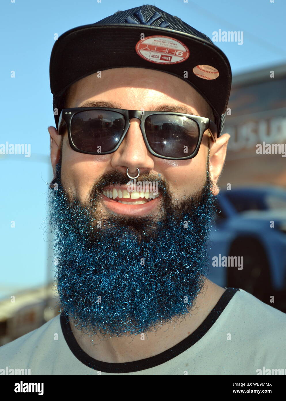 A man with a blue tinted beard and a metal ring in his nose is one of ...