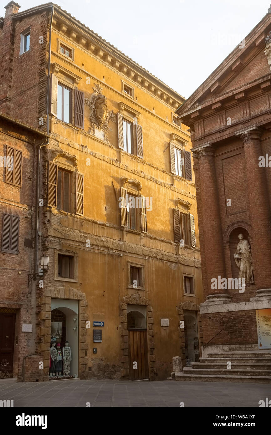 Sunrise over an empty street and piazza with old brick buildings and ...