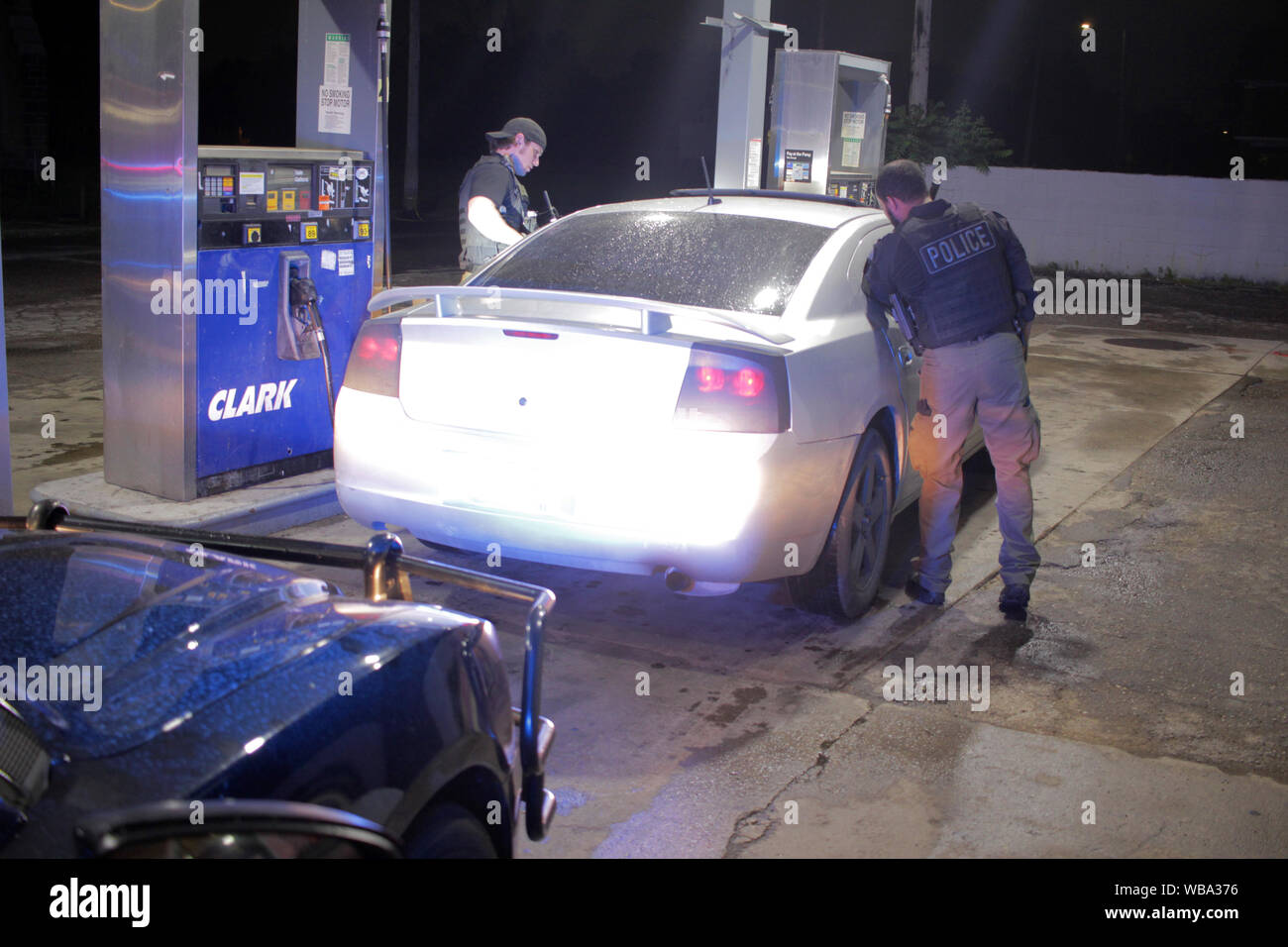 Detroit police officers approach a suspect vehilce at a gas station in ...