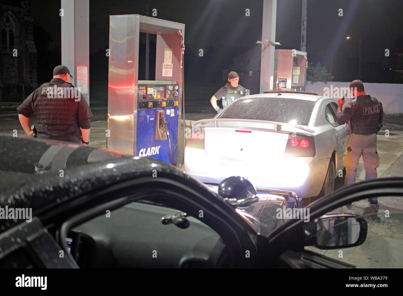 Detroit police officers approach a suspect vehilce at a gas station in ...