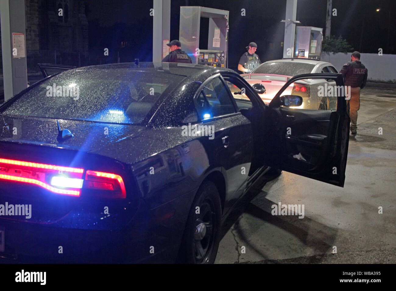 Detroit police officers approach a suspect vehilce at a gas station in ...