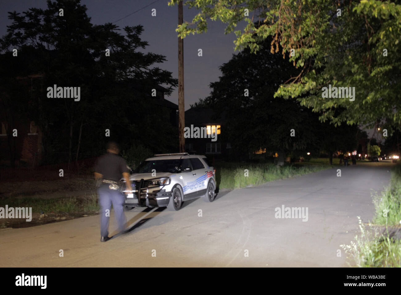 A cop approaches his car in a dark street at night in Detroit, Michigan ...
