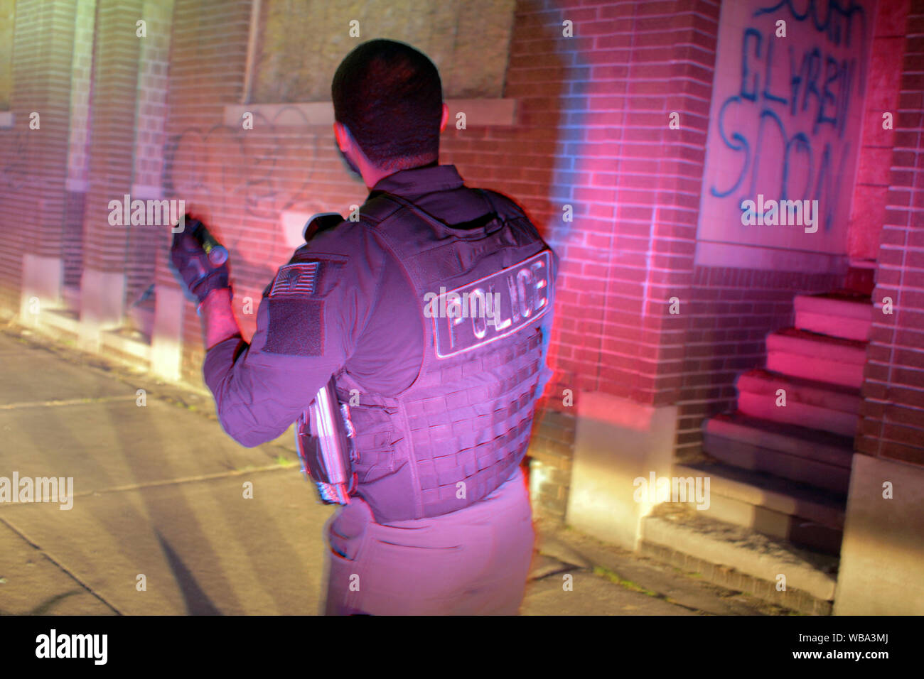 A police officer checks gang graffiti at night, in Detroit, Michigan ...