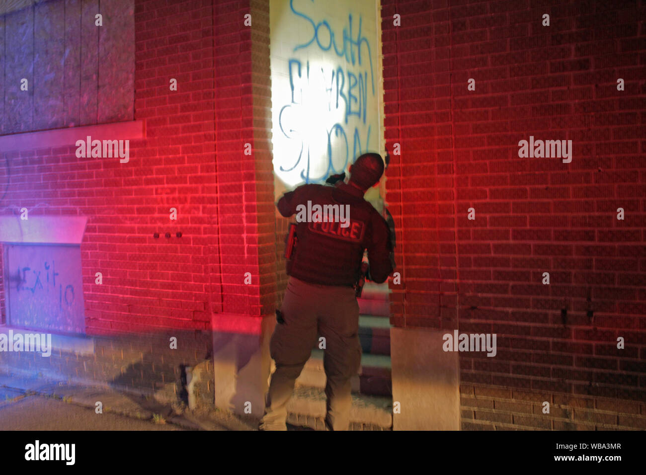 A police officer checks gang graffiti at night, in Detroit, Michigan ...