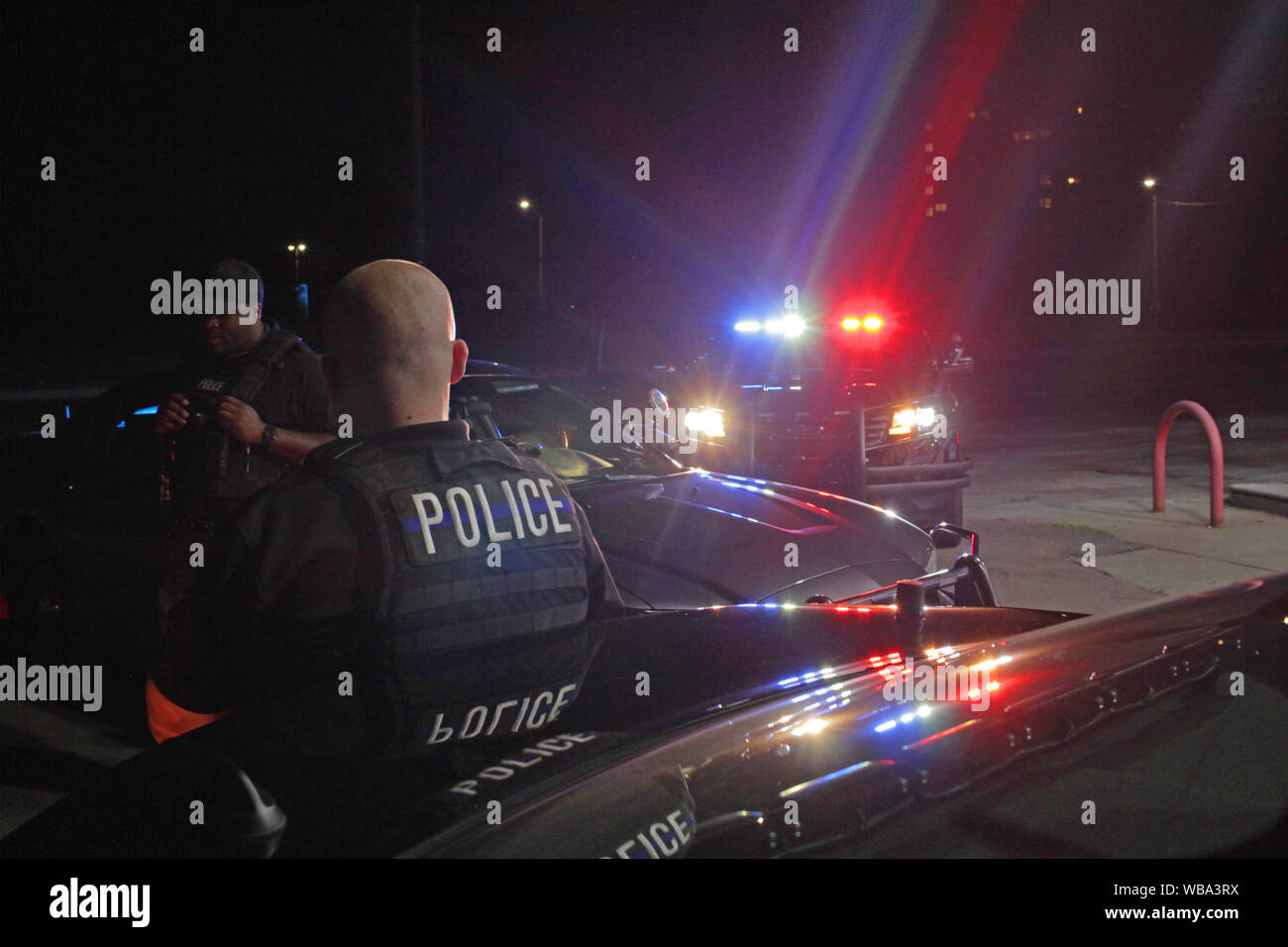 Detroit police officers speak at a gas station at night after dealing ...
