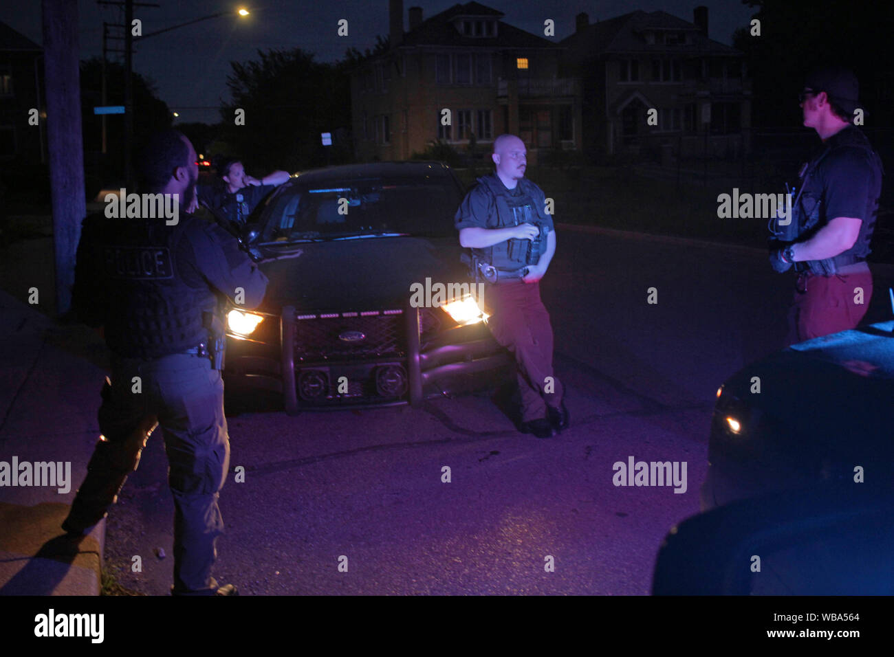 Detroit Special Operations police officers talk by their cars at night ...