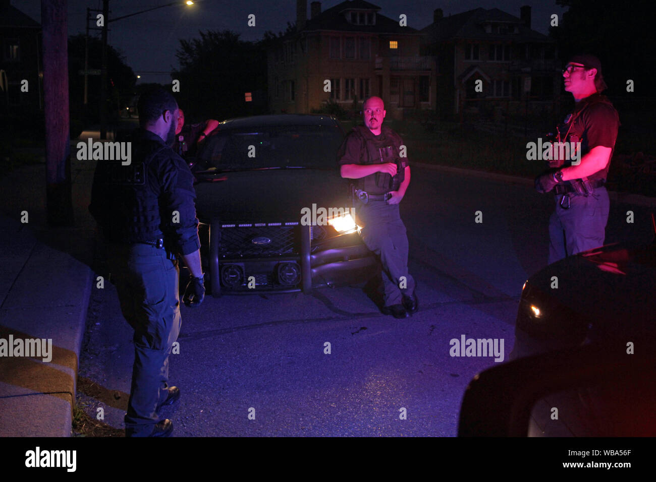 Detroit Special Operations police officers talk by their cars at night ...