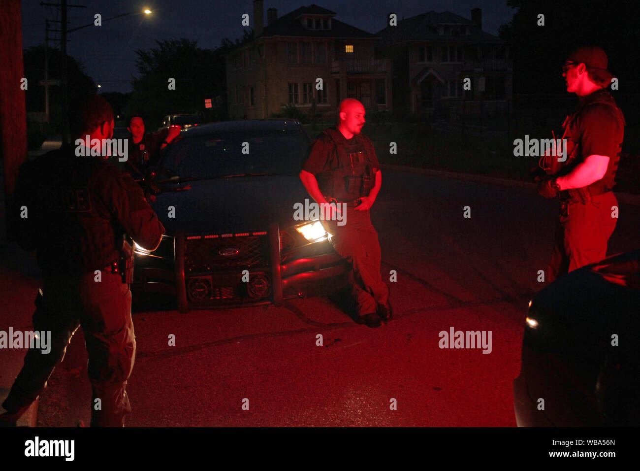 Detroit Special Operations police officers talk by their cars at night ...