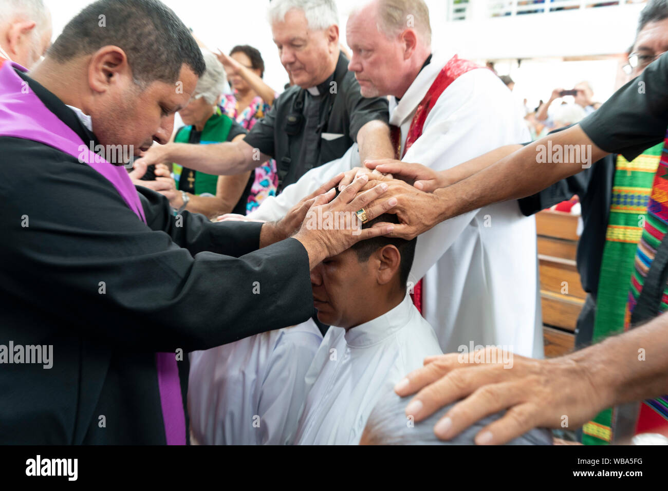 Traditional laying on of hands blessing during ordination ceremony for ...