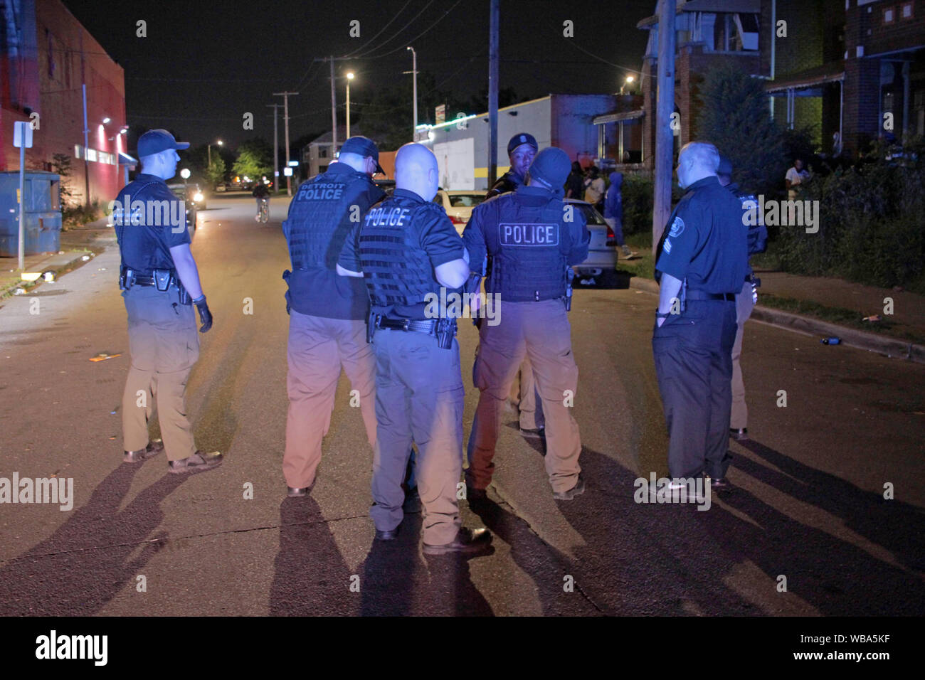 Group of Detroit police Special Ops officers stand in a street, trying ...