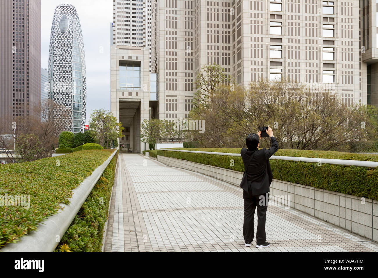 A Japanese male office worker or salaryman takes a photo with a ...