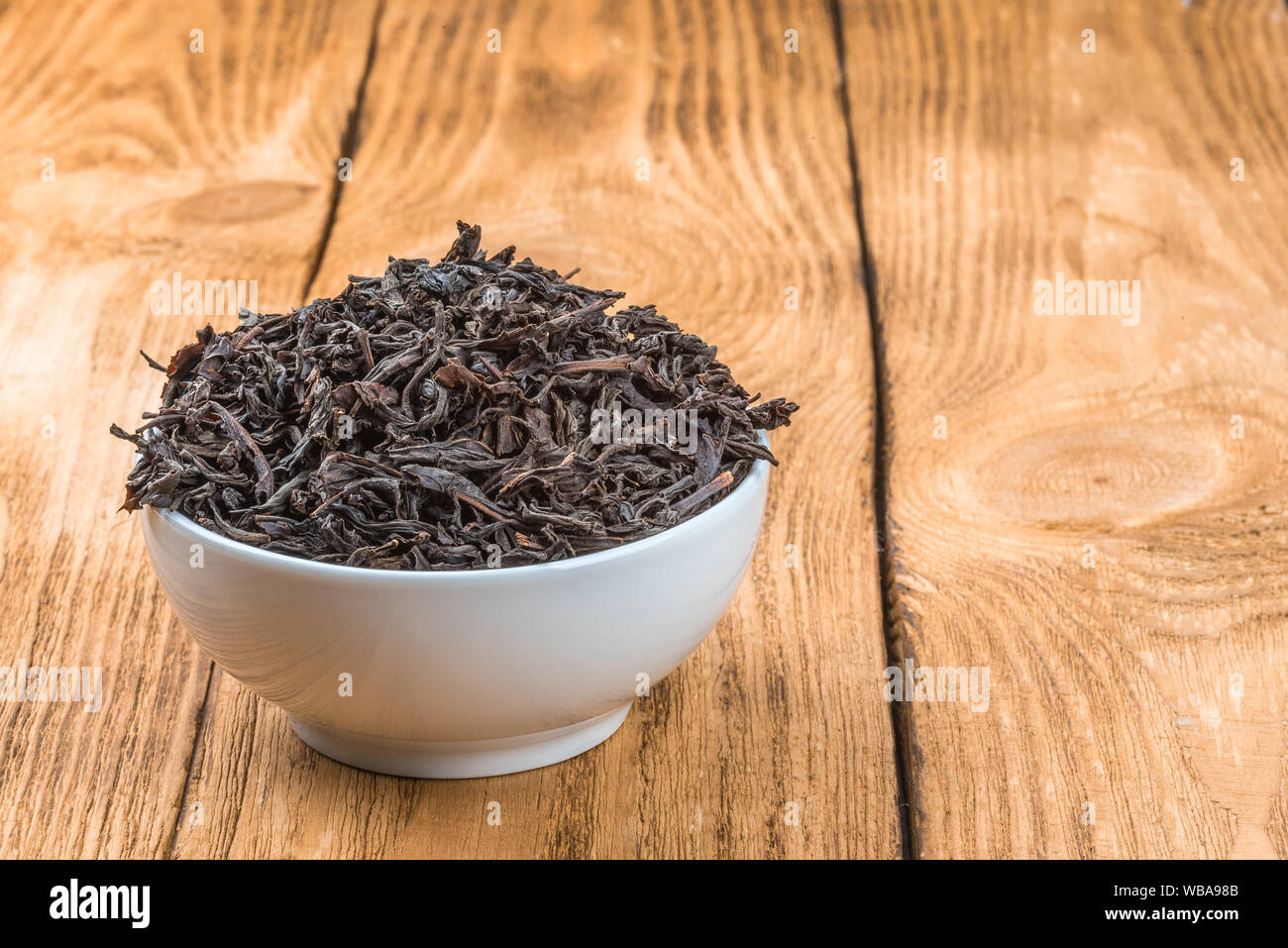 Dried tea is poured into a ceramic cup on a wooden plank table Stock ...