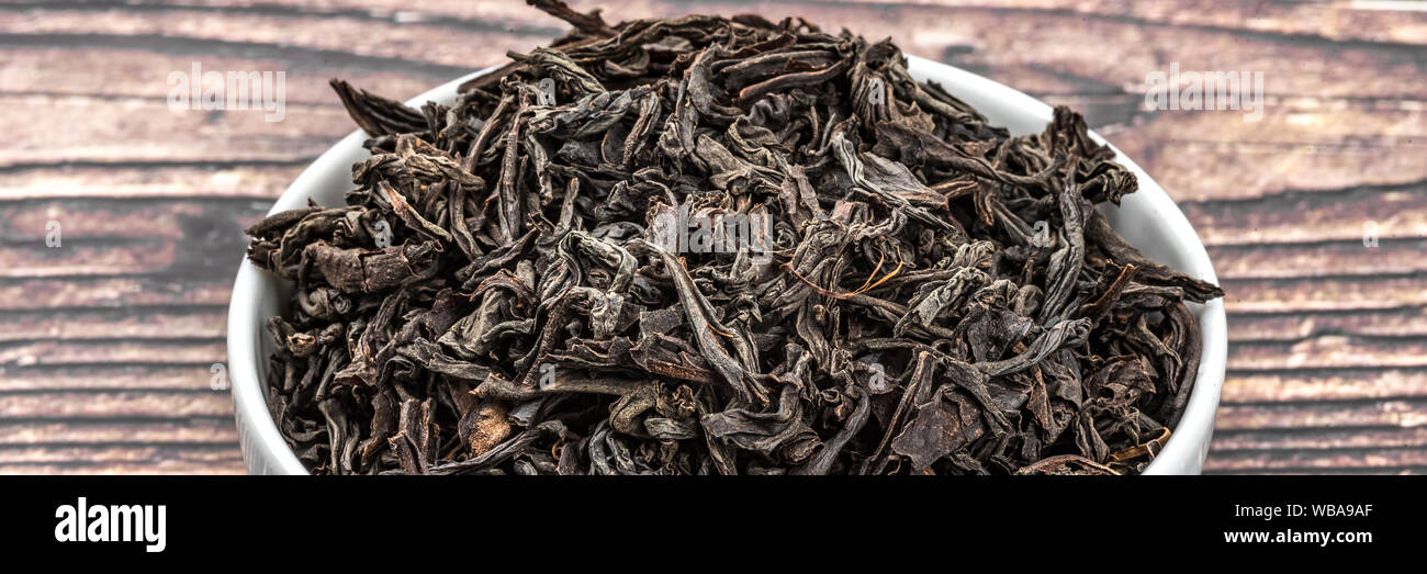 Dried tea is poured into a ceramic cup on a wooden plank table Stock ...