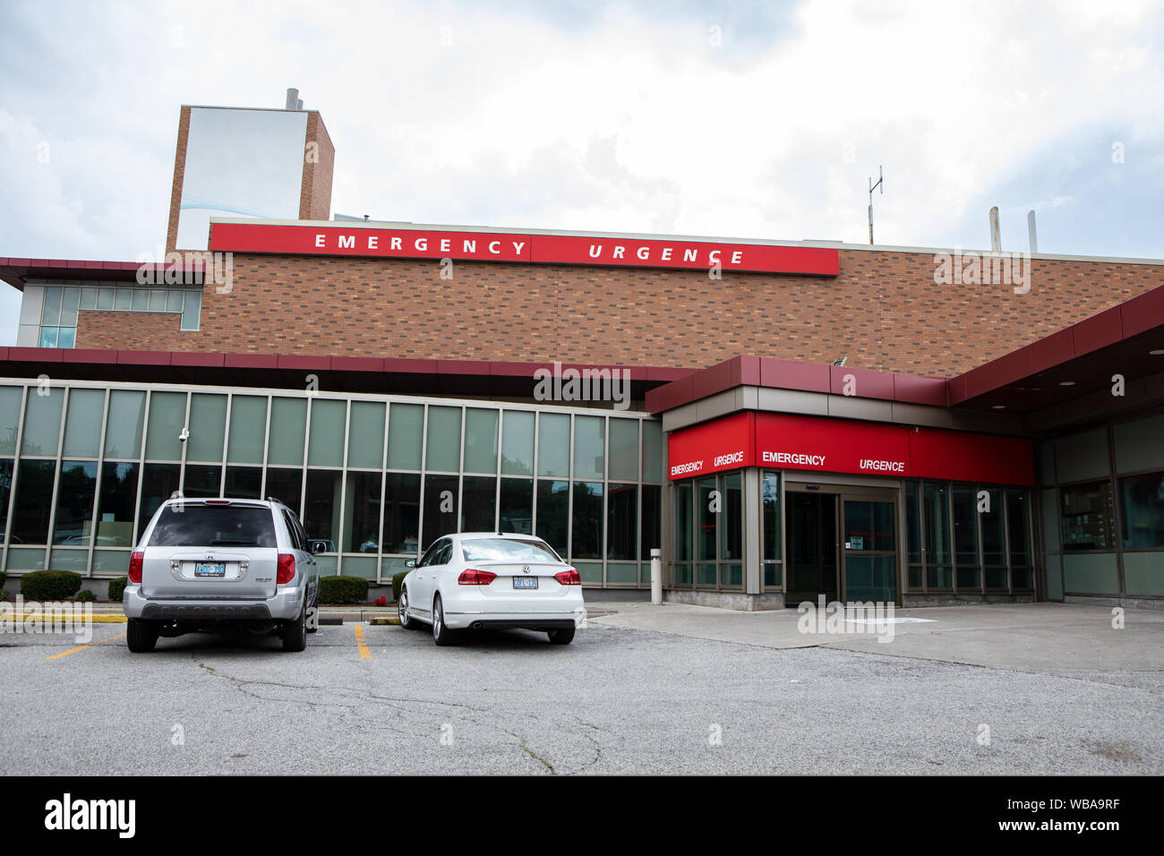 Hospital Emergency Entrance with Parking Spaces and Cars on a cloudy ...