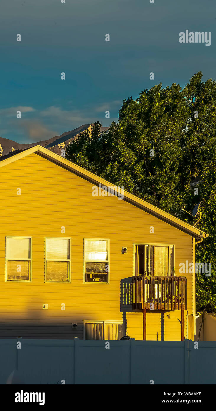 Vertical frame Sunlit house with cream wall and small wooden balcony ...