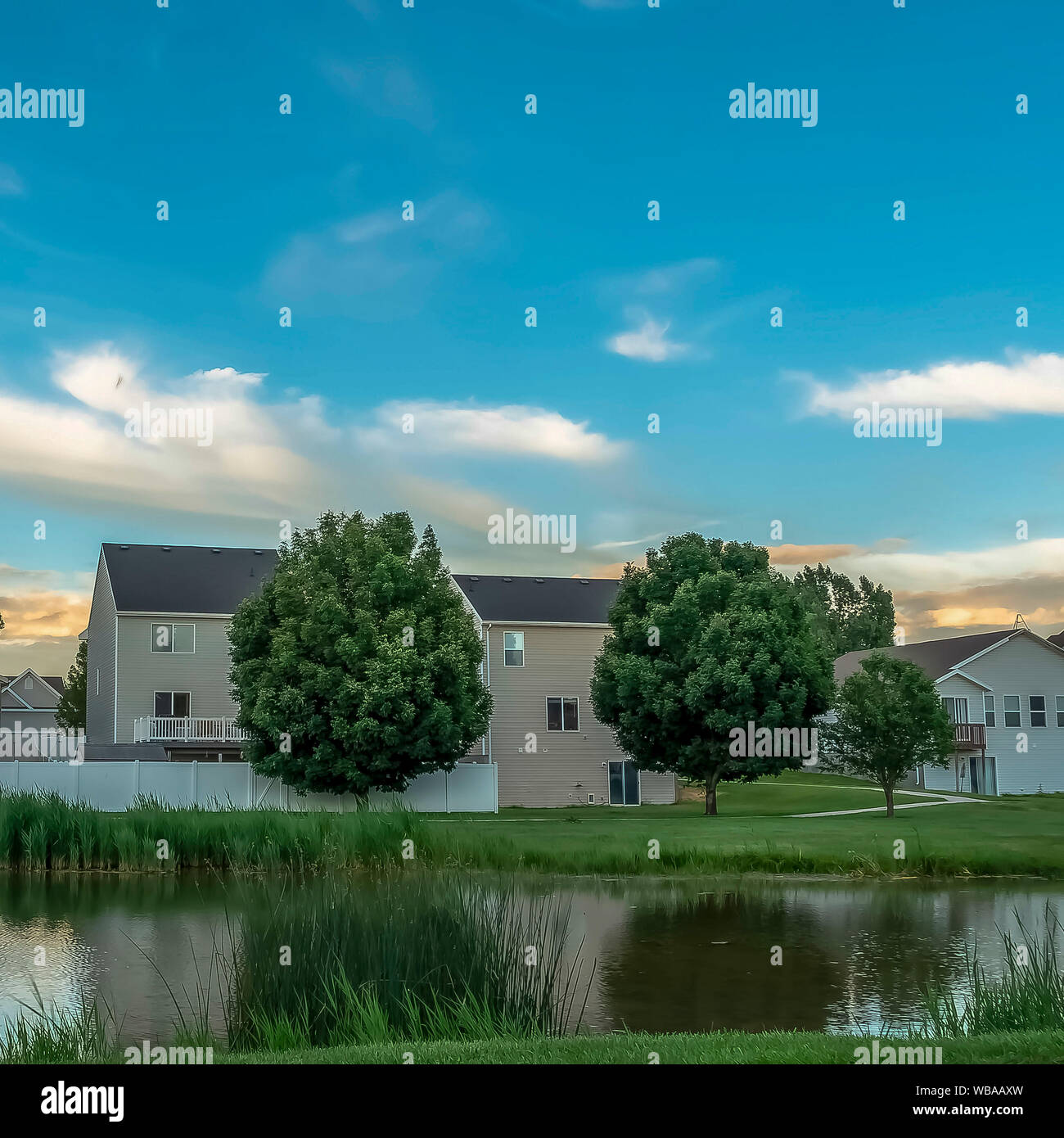 Square Pathway along a shiny pond on a grassy terrain with homes in the ...
