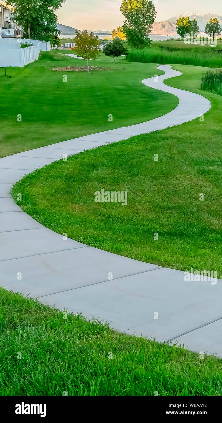 Vertical Winding footpath along a shiny pond in front of homes viewed ...