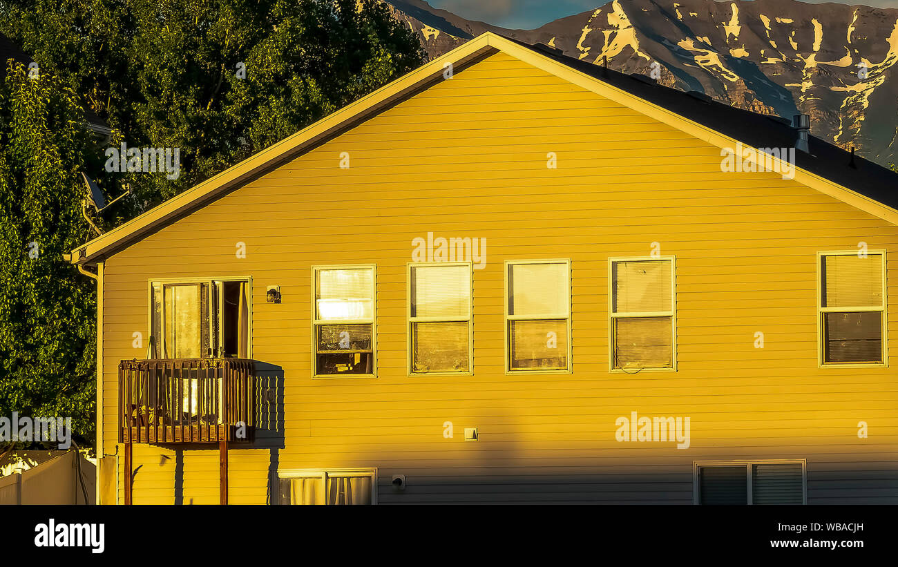 Panorama Sunlit house with cream wall and small wooden balcony inside a ...