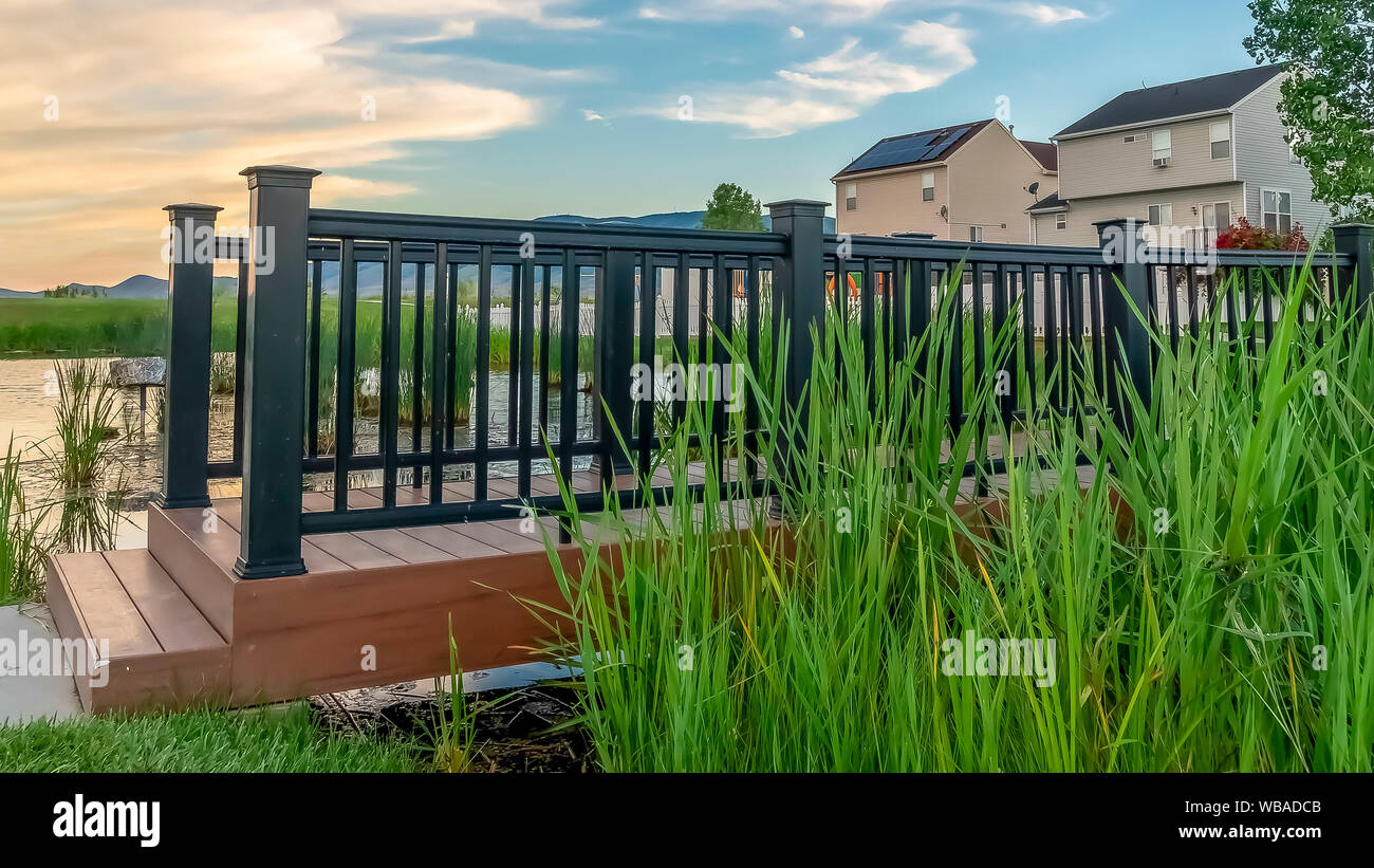 Panorama Side view of bridge over a pond on a scenic park with homes in ...