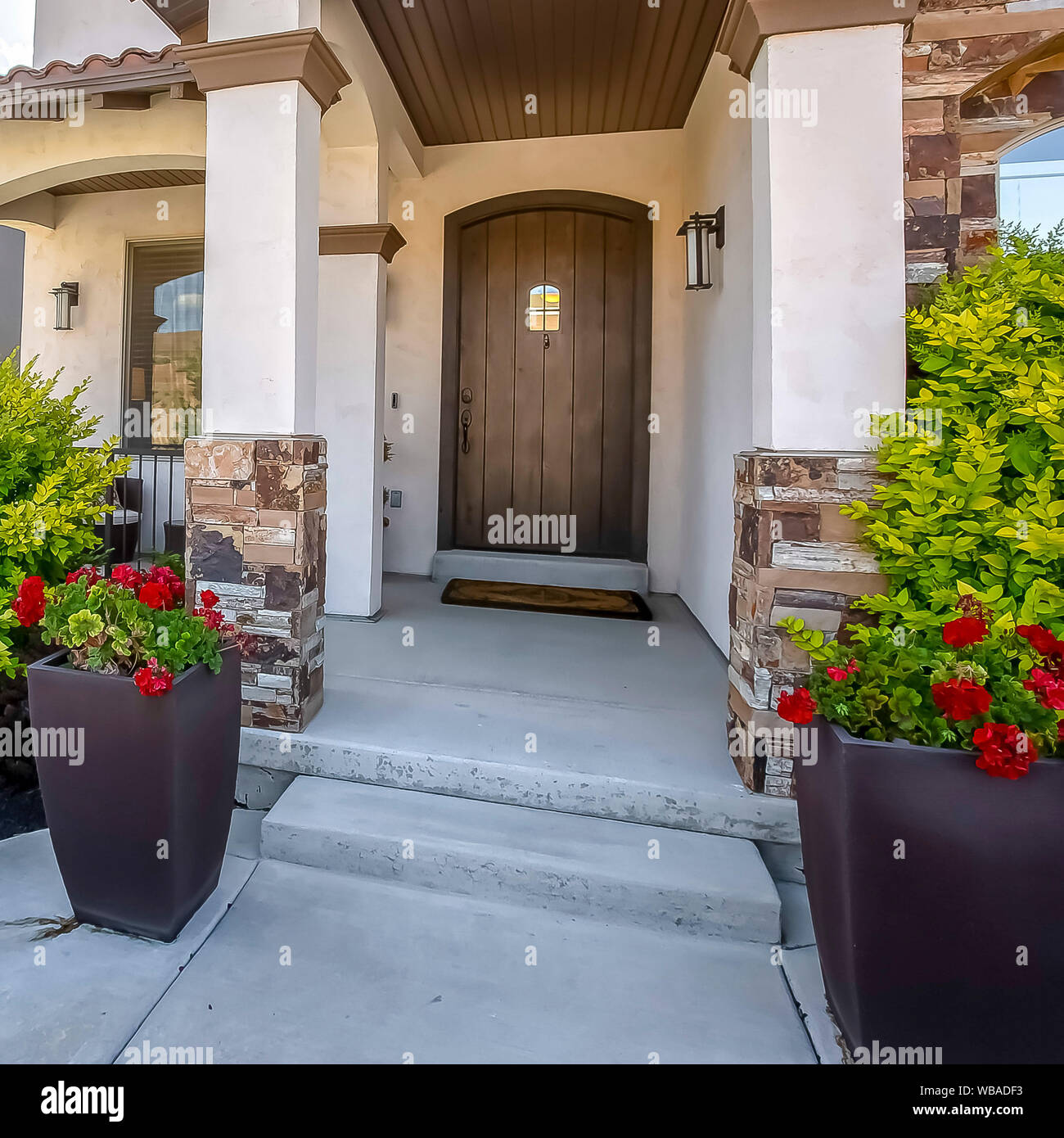 Square frame Home facade with arched entrance flanked by vibrant plants ...