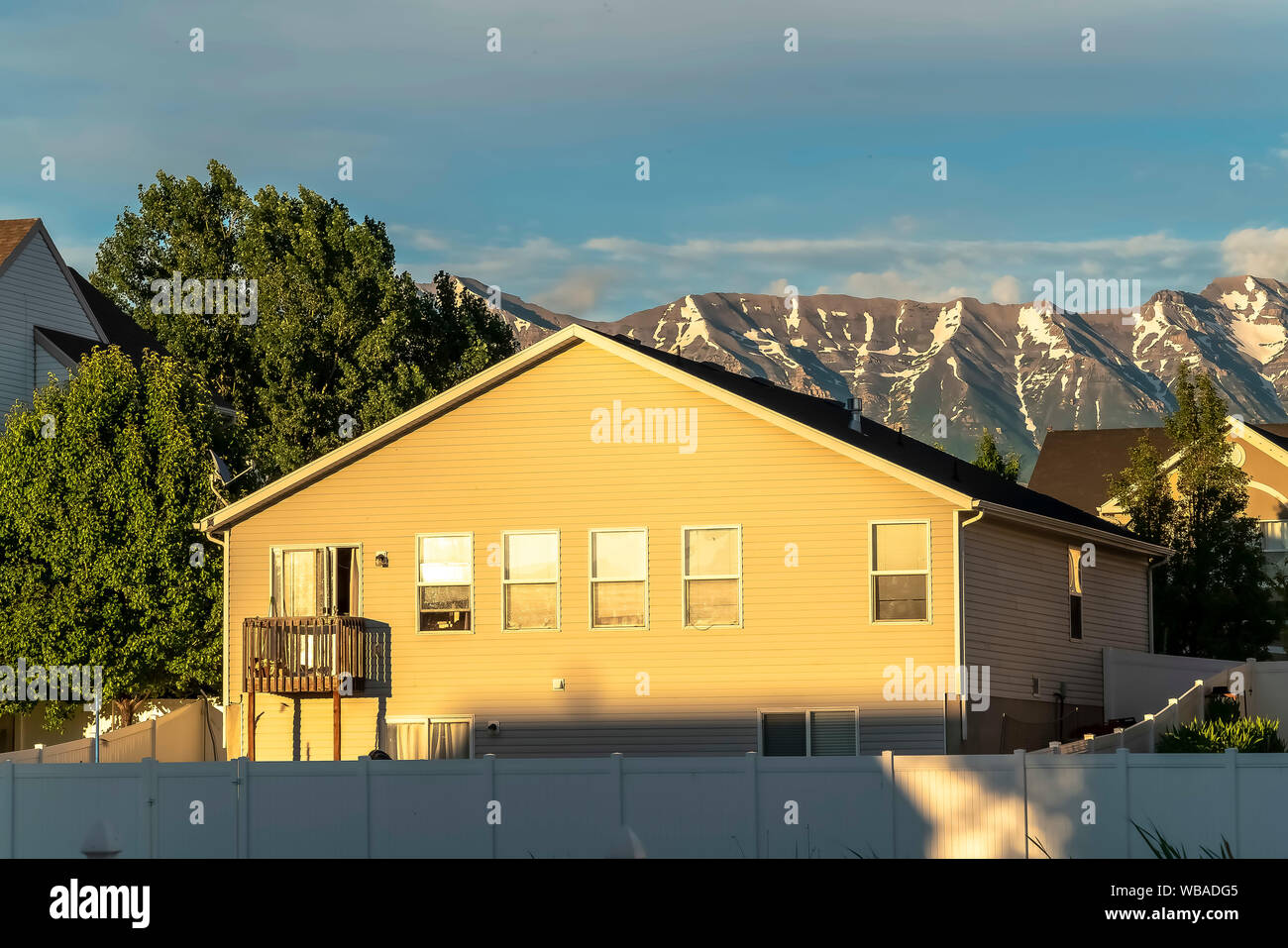 Sunlit house with cream wall and small wooden balcony inside a white ...