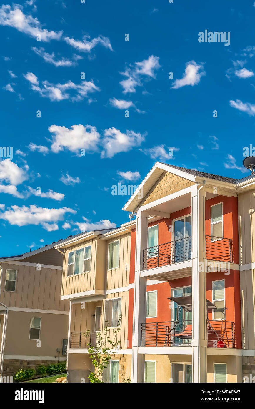 Multi storey home exterior with sunlit balconies and white and orange ...