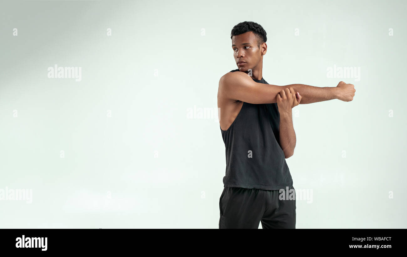 Warming up. Strong young afro american man stretching his arm while ...