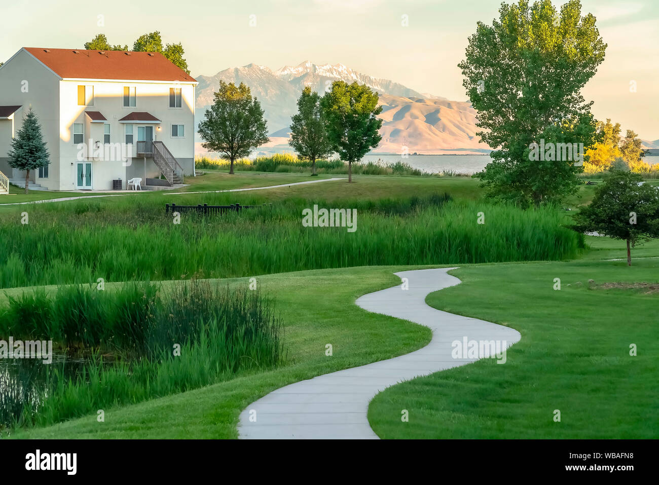 Pathway and pond on grassy terrain with homes lake and mountain ...