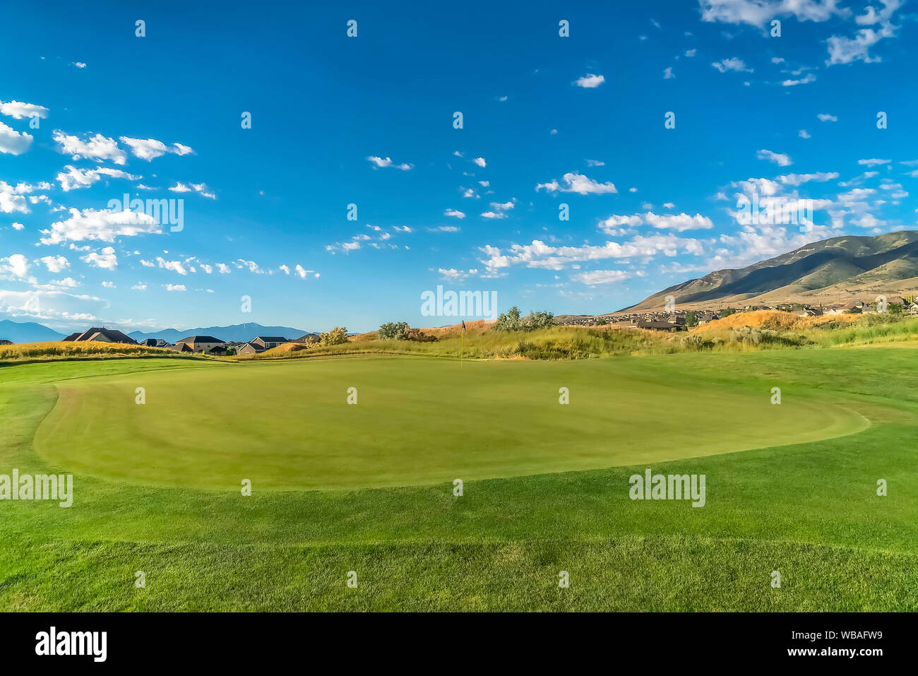 Golf course with vivid green fairway under blue sky and clouds on a ...