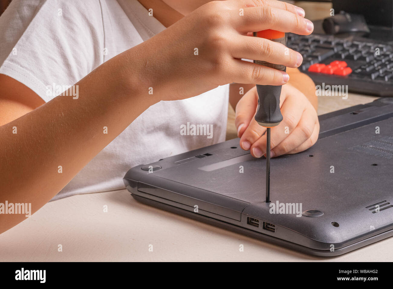 A boy of 10 years old is sorting a laptop for cleaning and maintenance ...