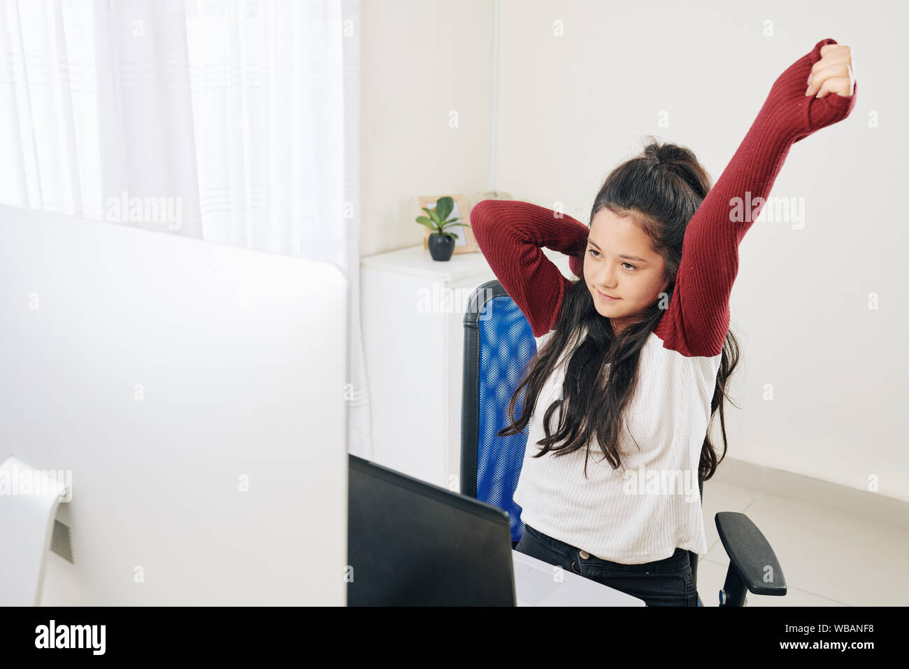 Stretching tired teenage girl looking at programming code on screen of ...