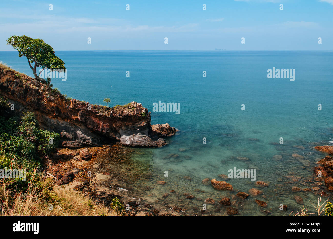 Rock cliff with lone tree and blue clear water sea in Koh Lanta, Krabi ...
