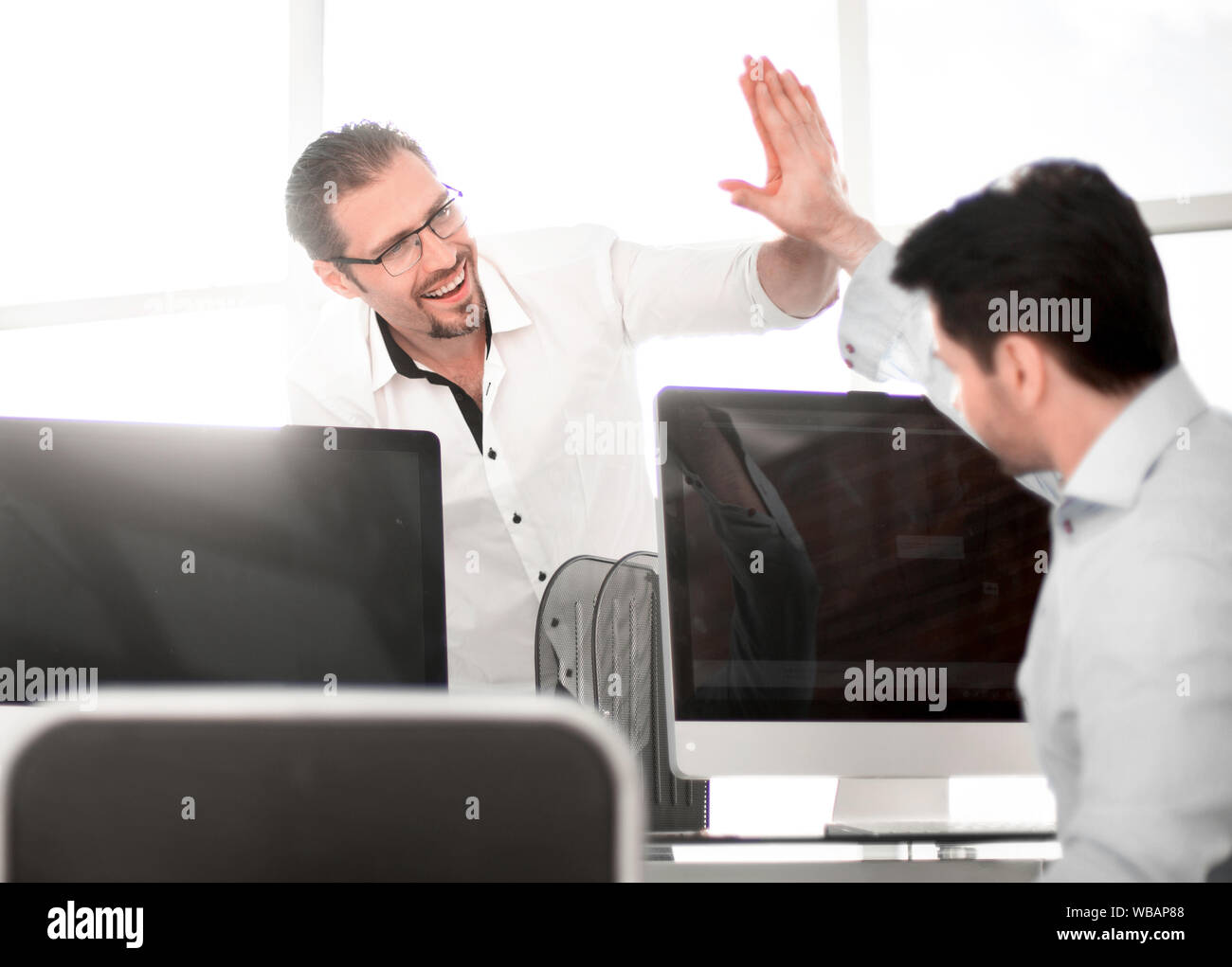 employees give each other a high five over the computer Desk Stock ...