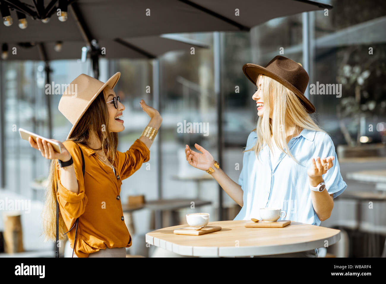 Meeting of a two female best friends at the cafe outdoors, hugging and ...