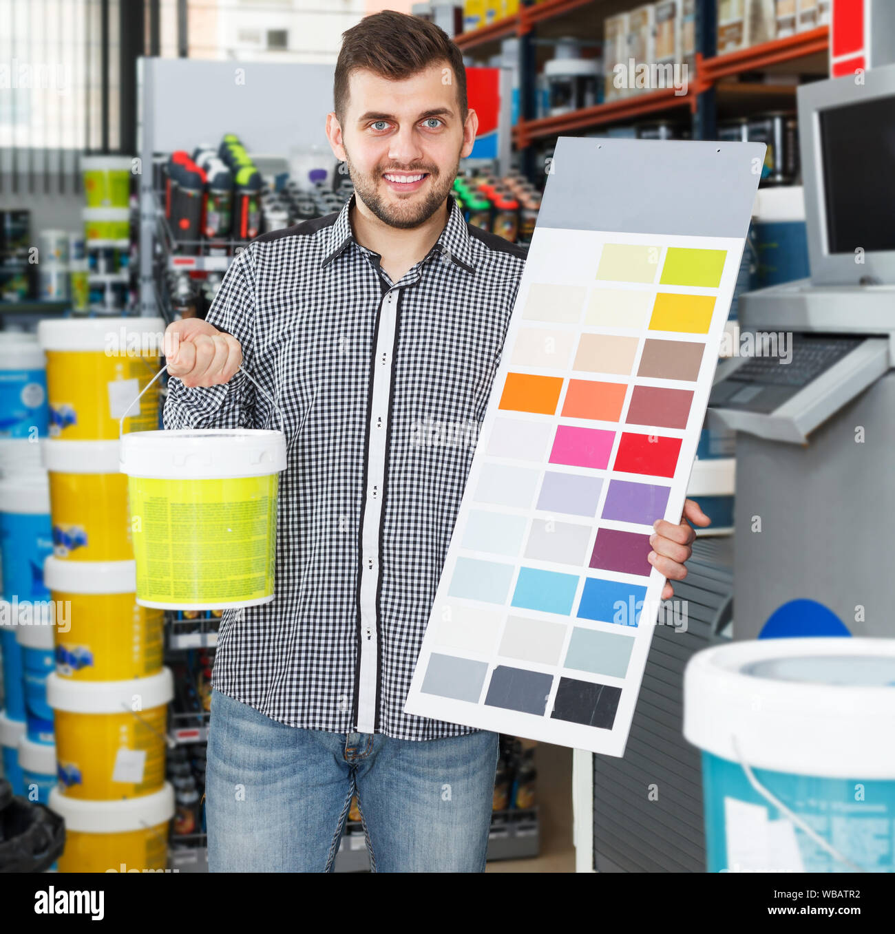 Young positive man choosing color for painting using palette scheme in ...