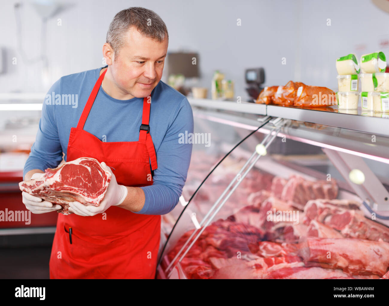 Positive man seller showing fresh meat at meat market Stock Photo - Alamy